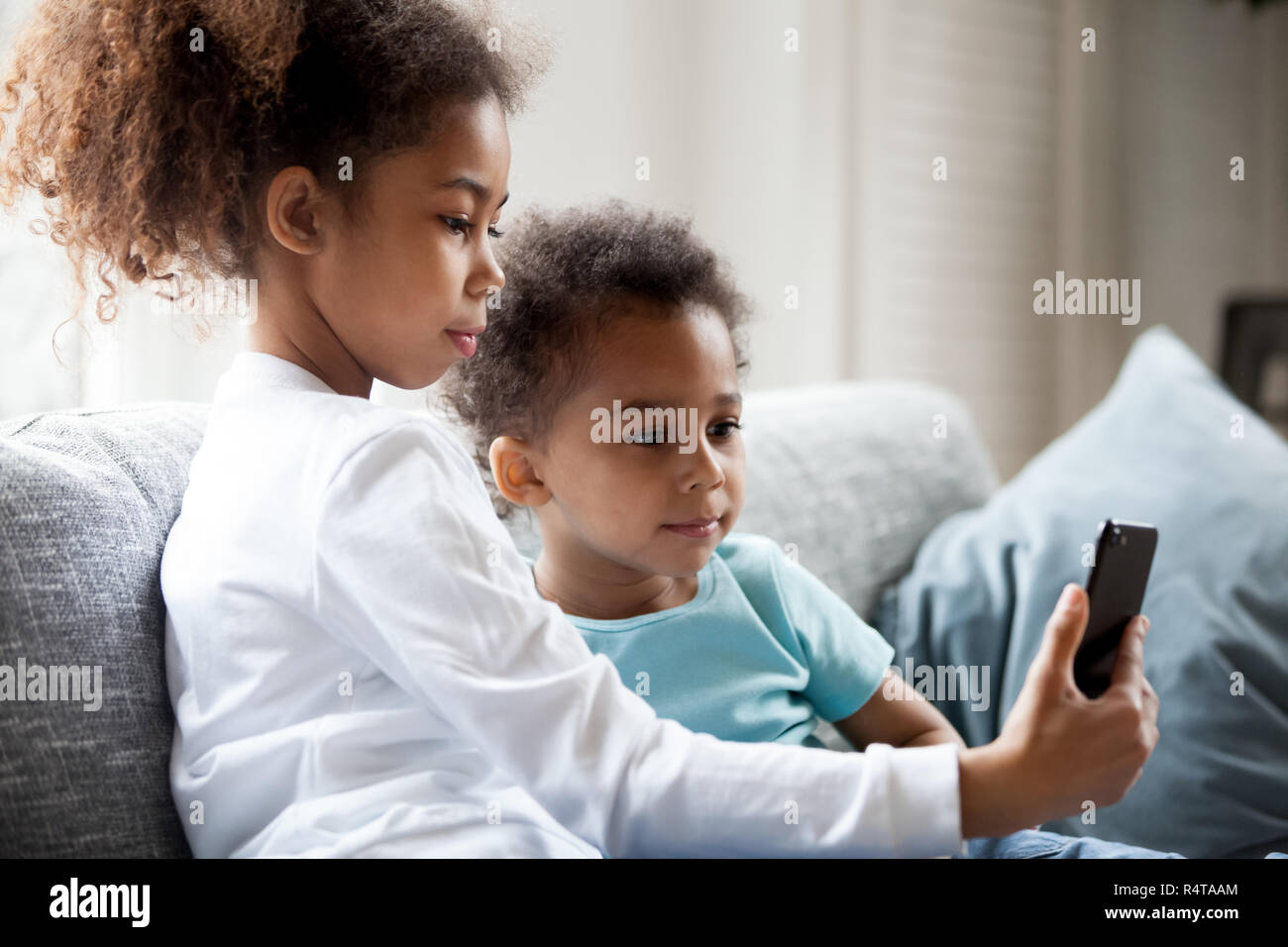 Pretty African American children is using smartphone Stock Photo - Alamy