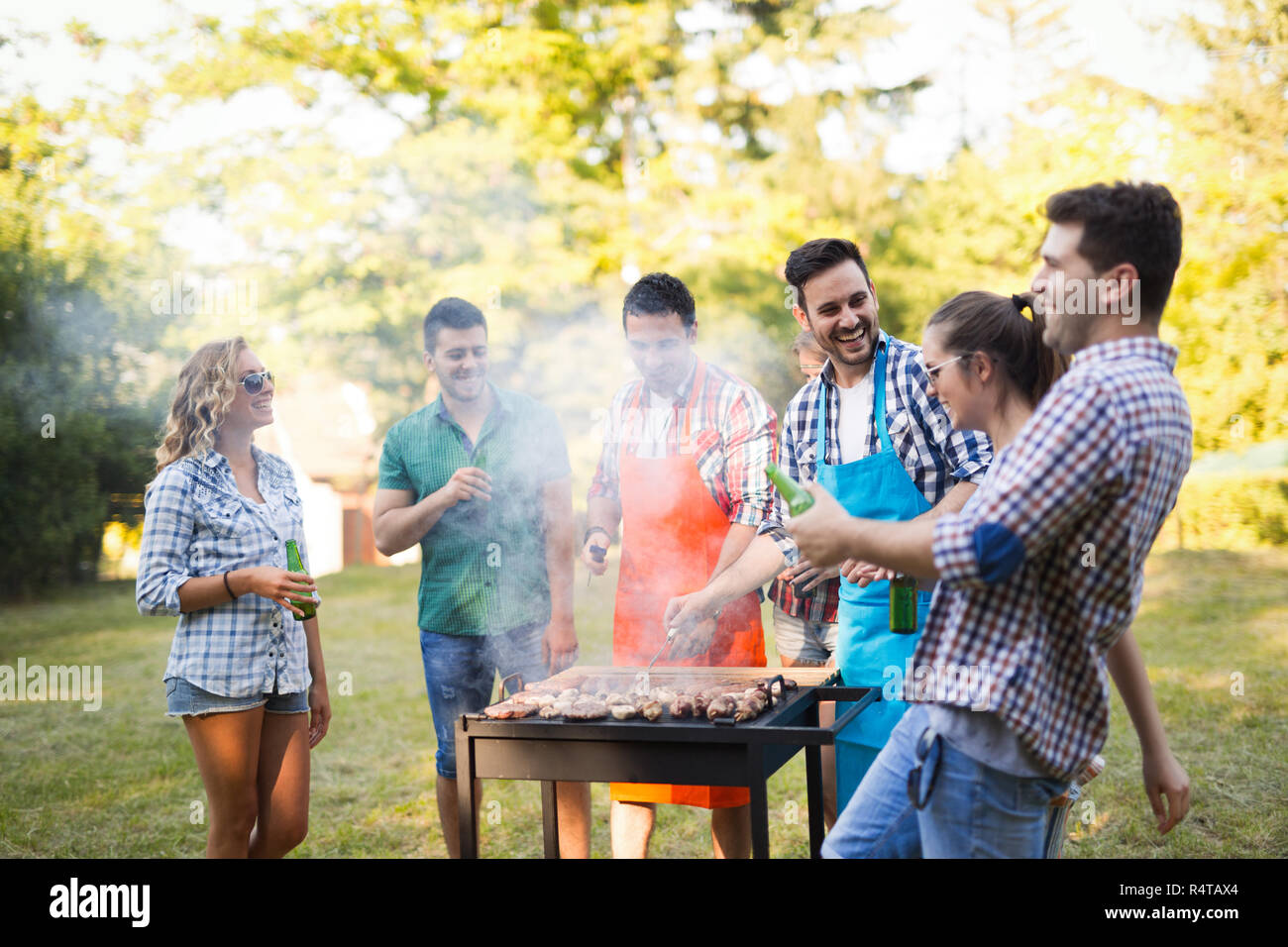 Happy and young friends enjoying barbecue party Stock Photo - Alamy