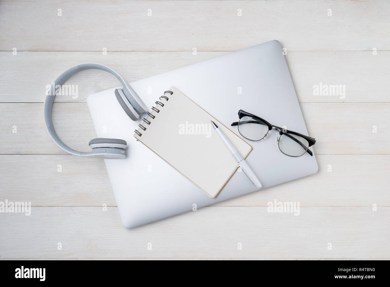 Notepad and computer keyboard on white table with headphone. View from ...