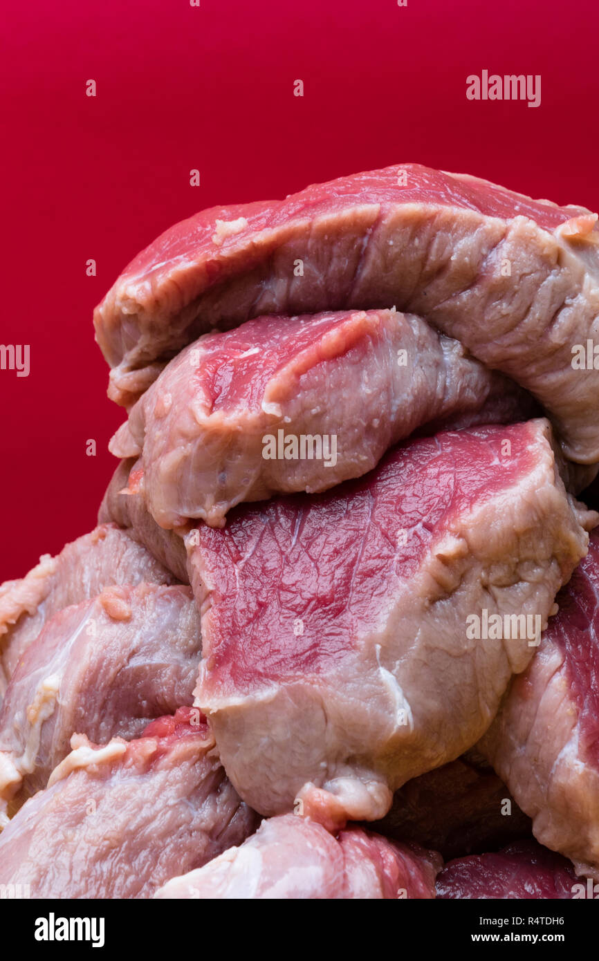 pieces of raw diced beef meat isolated on red background, protein ...