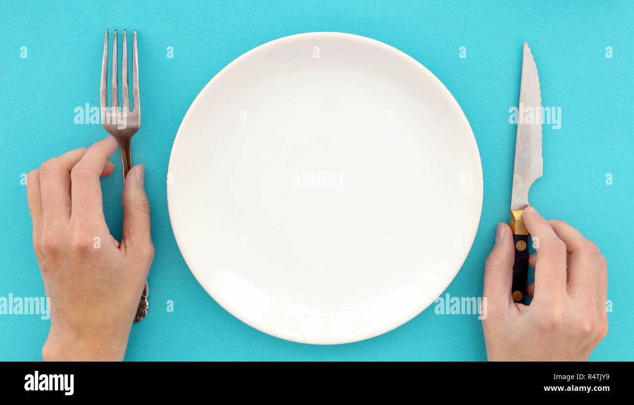 Female hands with cutlery and empty plate Stock Photo - Alamy