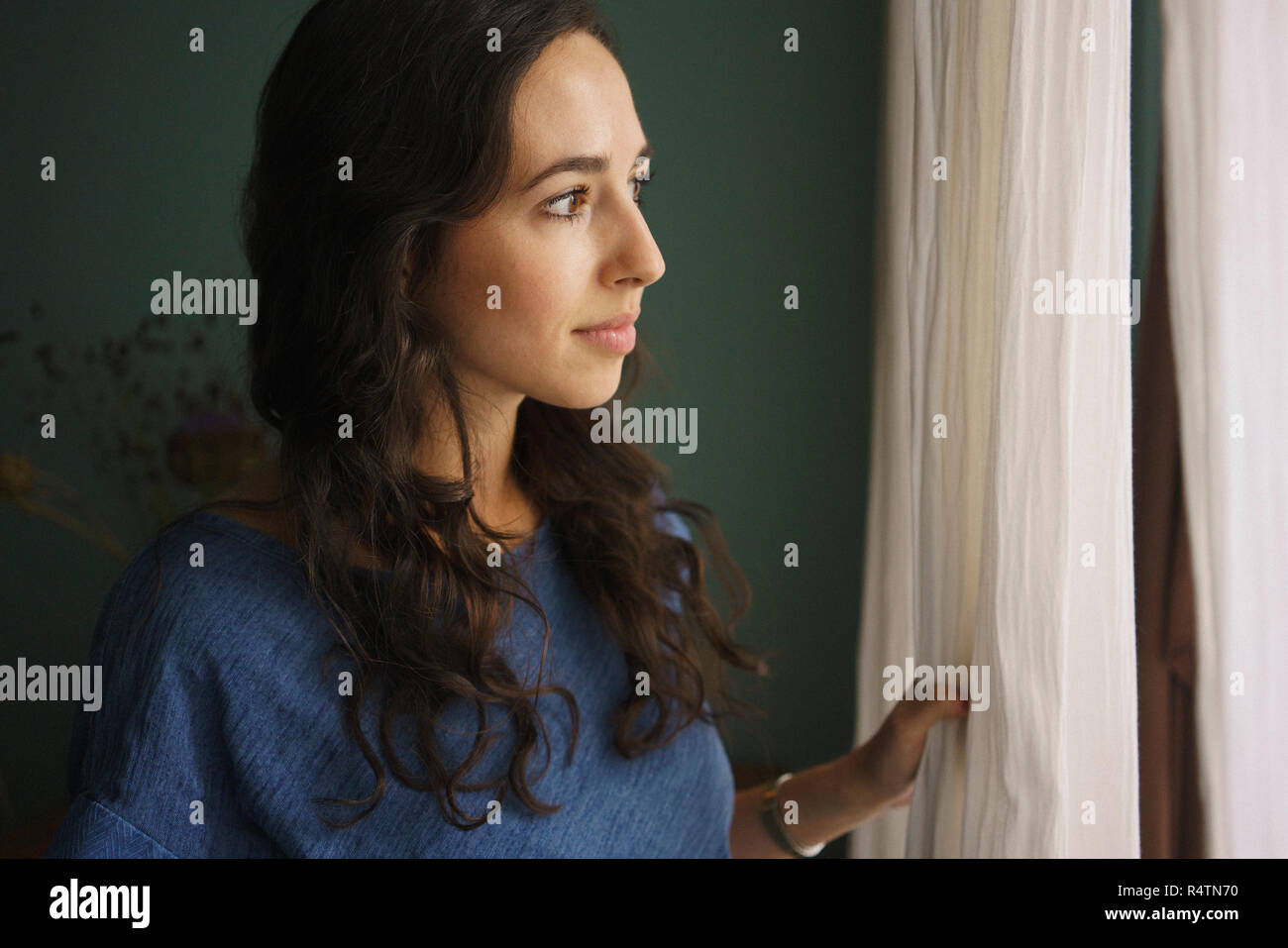 Brunette woman standing at the curtain hi-res stock photography and ...