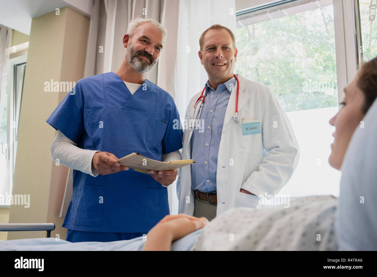 Doctors making rounds, talking with patient in hospital room Stock ...