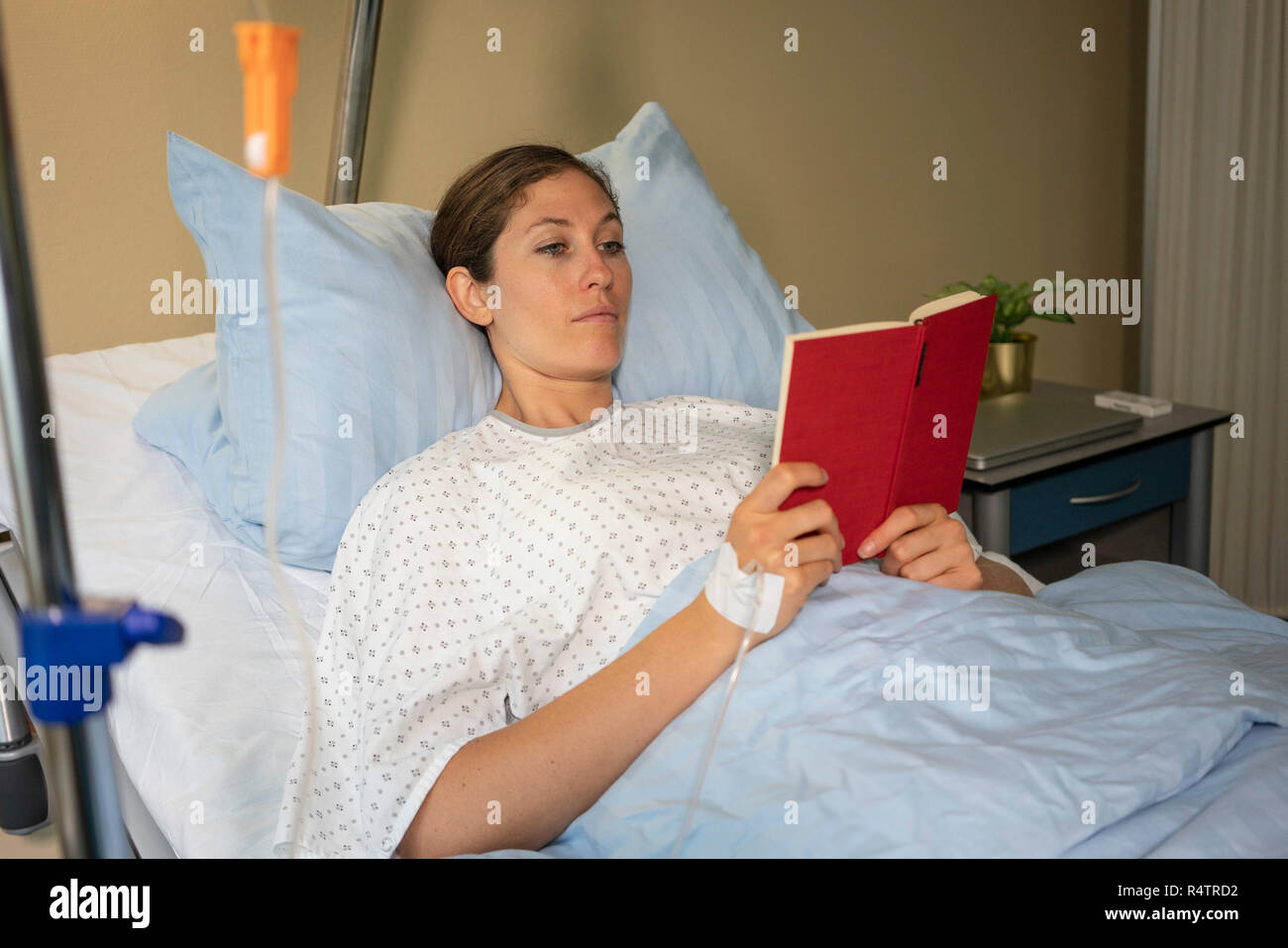 Female patient reading book, resting and recovering in hospital room ...