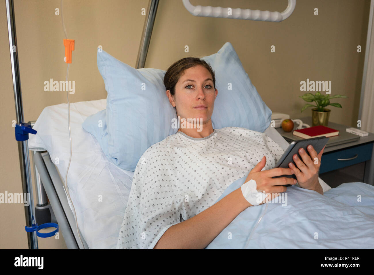 Portrait serious female patient with digital tablet, resting and ...