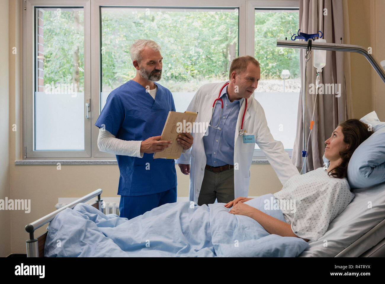 Doctors making rounds, talking with patient in hospital room Stock ...