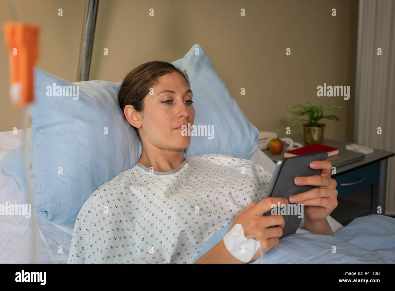 Female patient with digital tablet resting, recovering in hospital bed ...