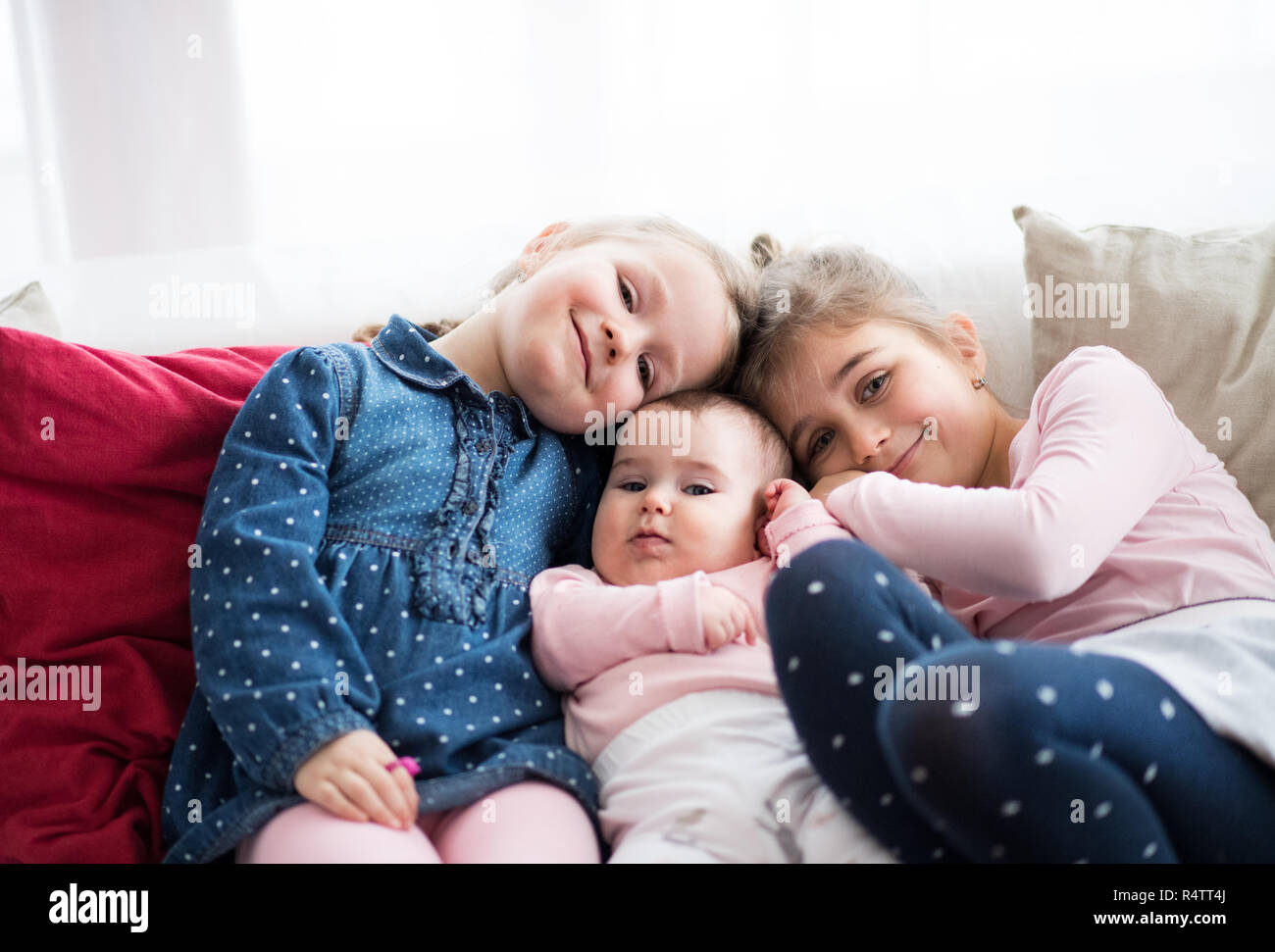 A portrait of three happy small girls sitting indoors on a sofa Stock ...