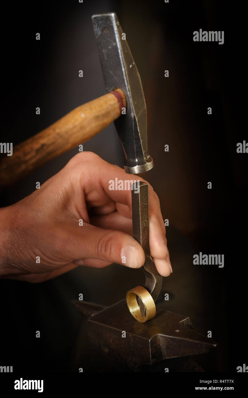 goldsmith hand punches a hallmark into a golden ring with a hammer on ...