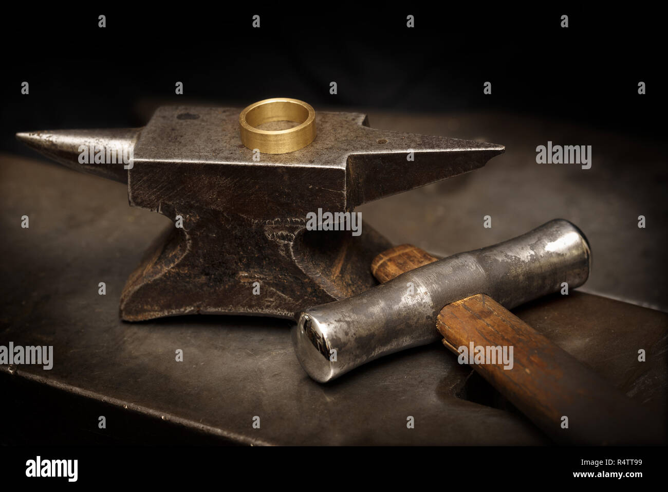 golden ring on an anvil and a goldsmith hammer in the jewelry workshop ...