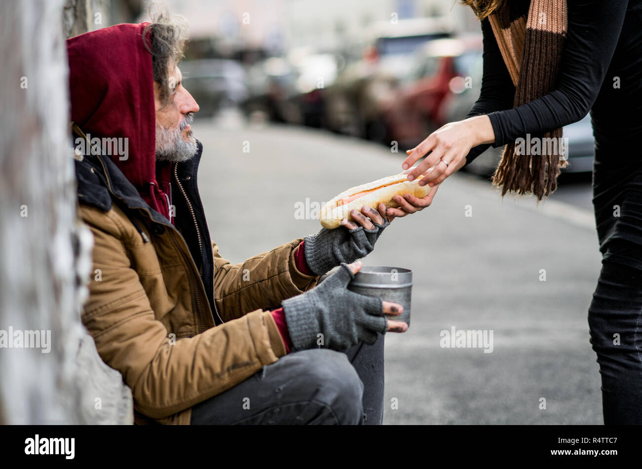 Unrecognizable Woman Giving Food To Homeless Beggar Man Sitting