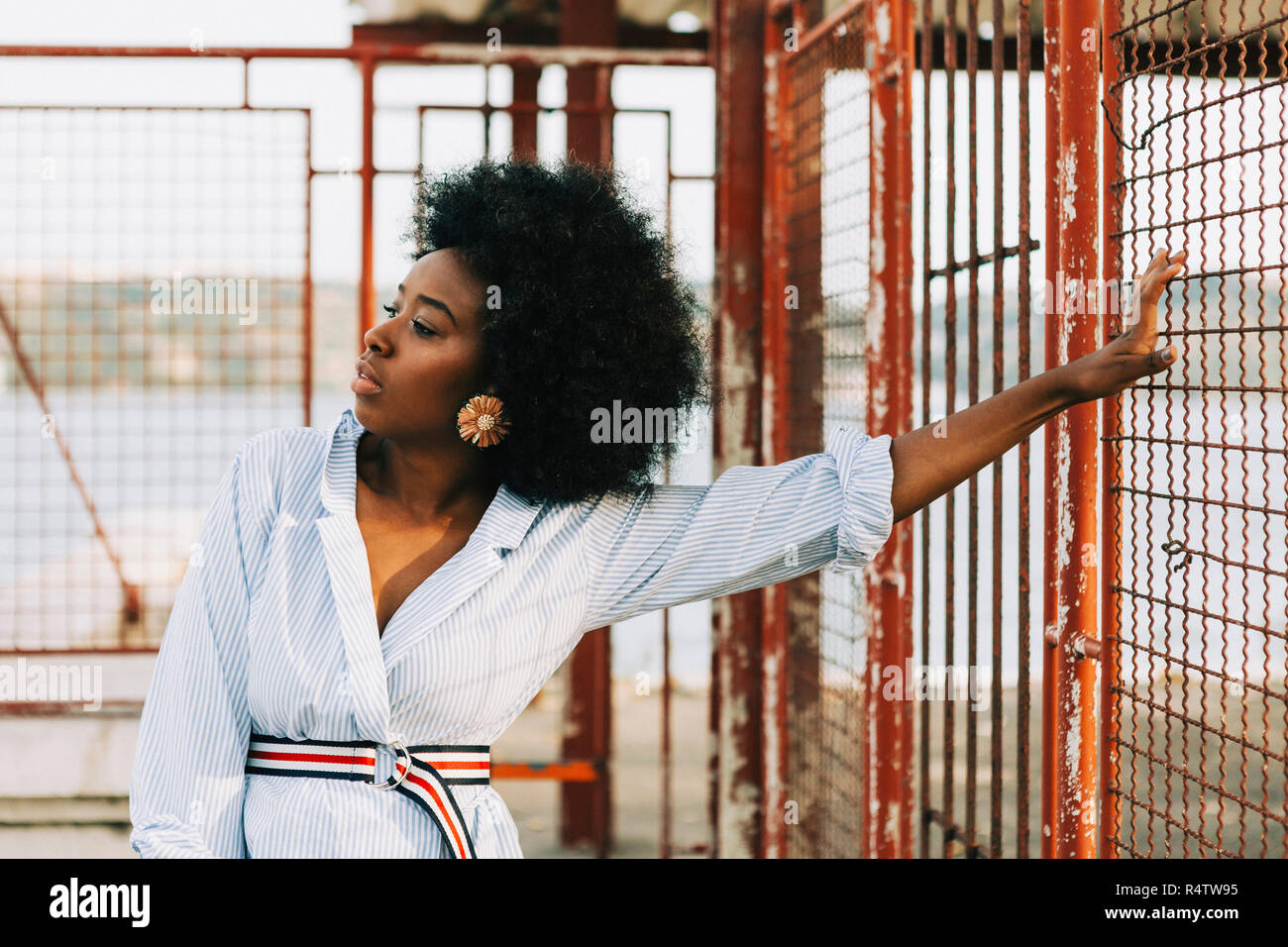 Confident young woman leaning on gate Stock Photo - Alamy