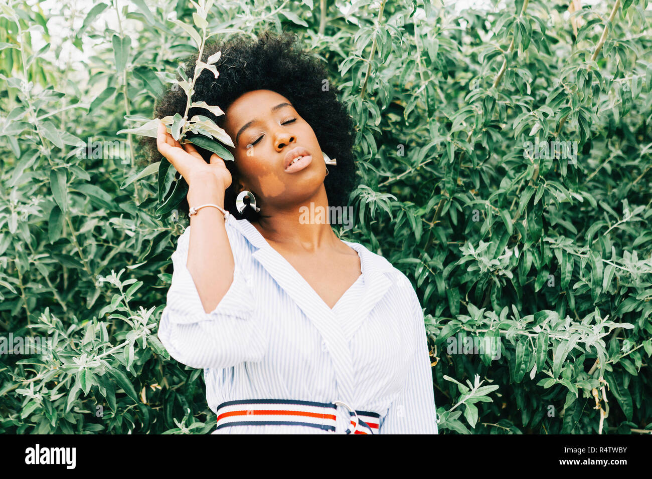 Serene woman standing at green bush Stock Photo - Alamy