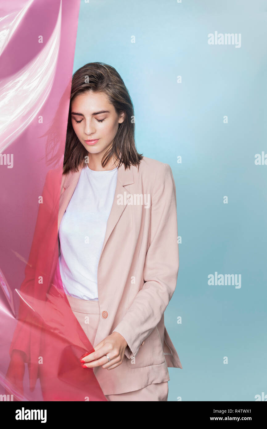 Portrait of a female fashion model posing with pink fabric and looking ...
