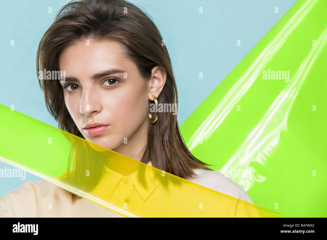Portrait of a female fashion model posing with yellow plastic sheets ...