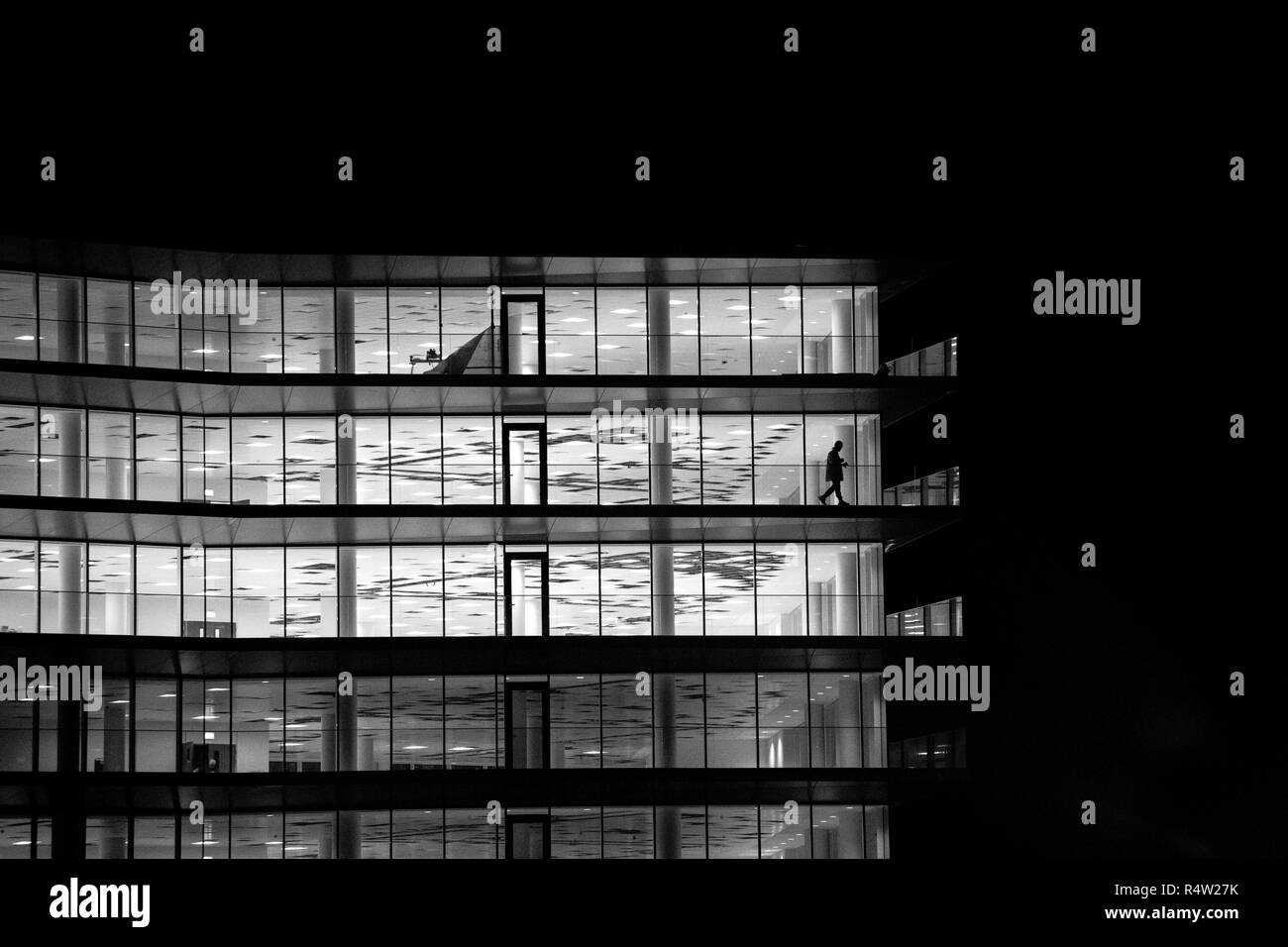 A lone figure walks along the balcony of an empty office building at ...