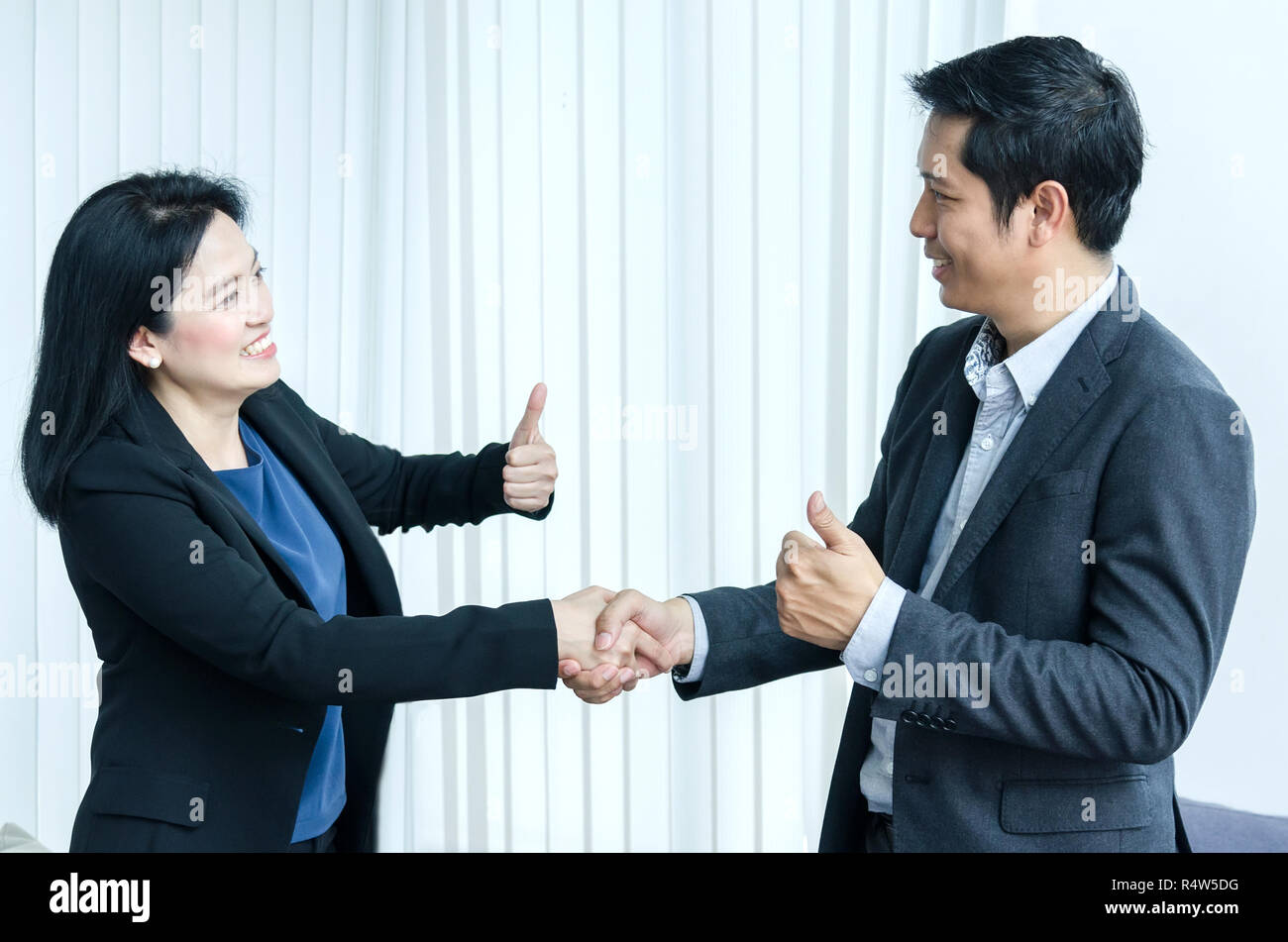 Asian woman and man handshake and showing thumbs up Stock Photo - Alamy