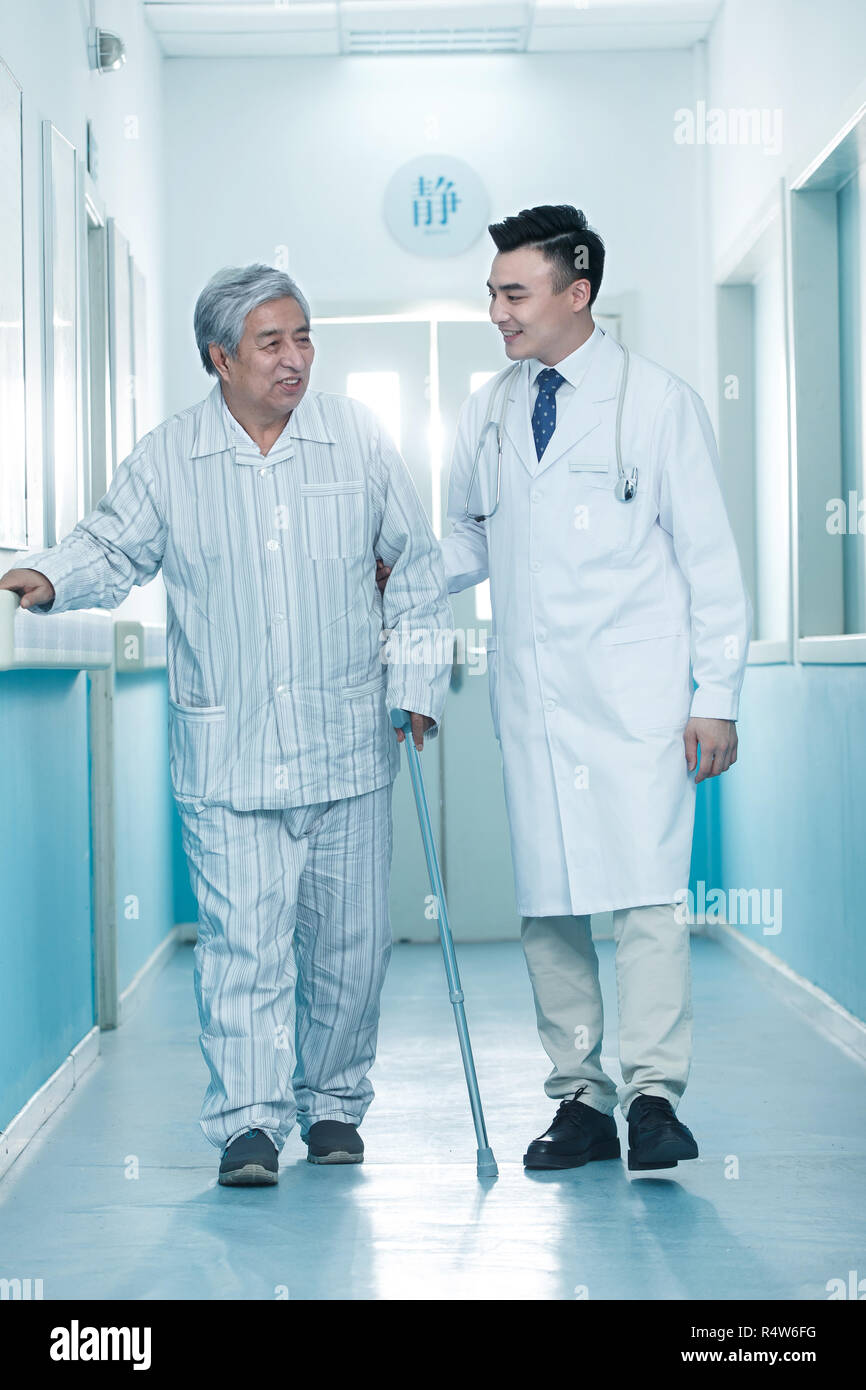 Doctor walking with patient in hospital corridor hi-res stock ...