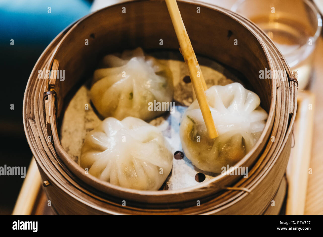 Chopsticks picking up a dim sum from a dim sum basket on a table Stock ...