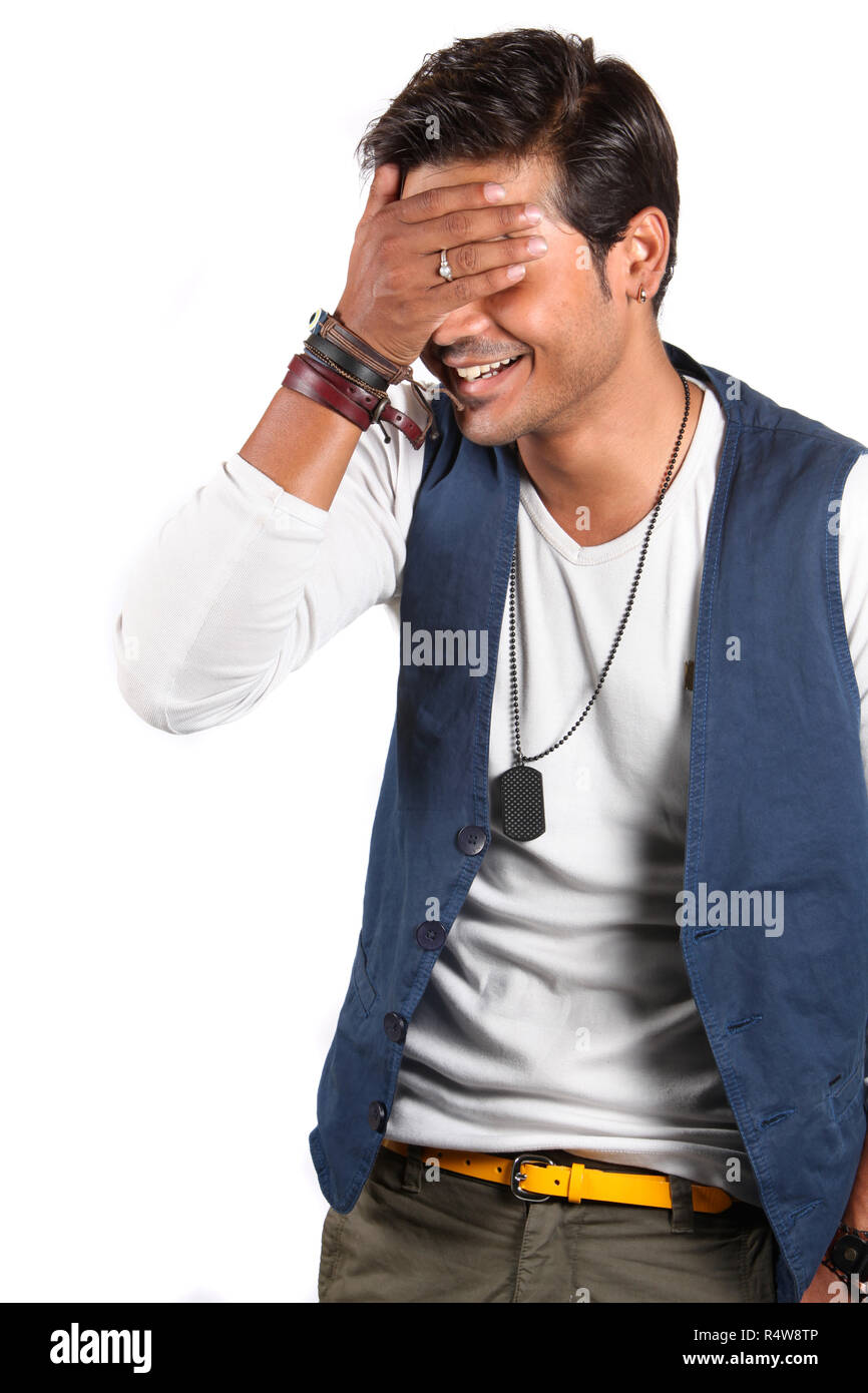 A young Indian guy embarrassed about a joke, on white studio background ...