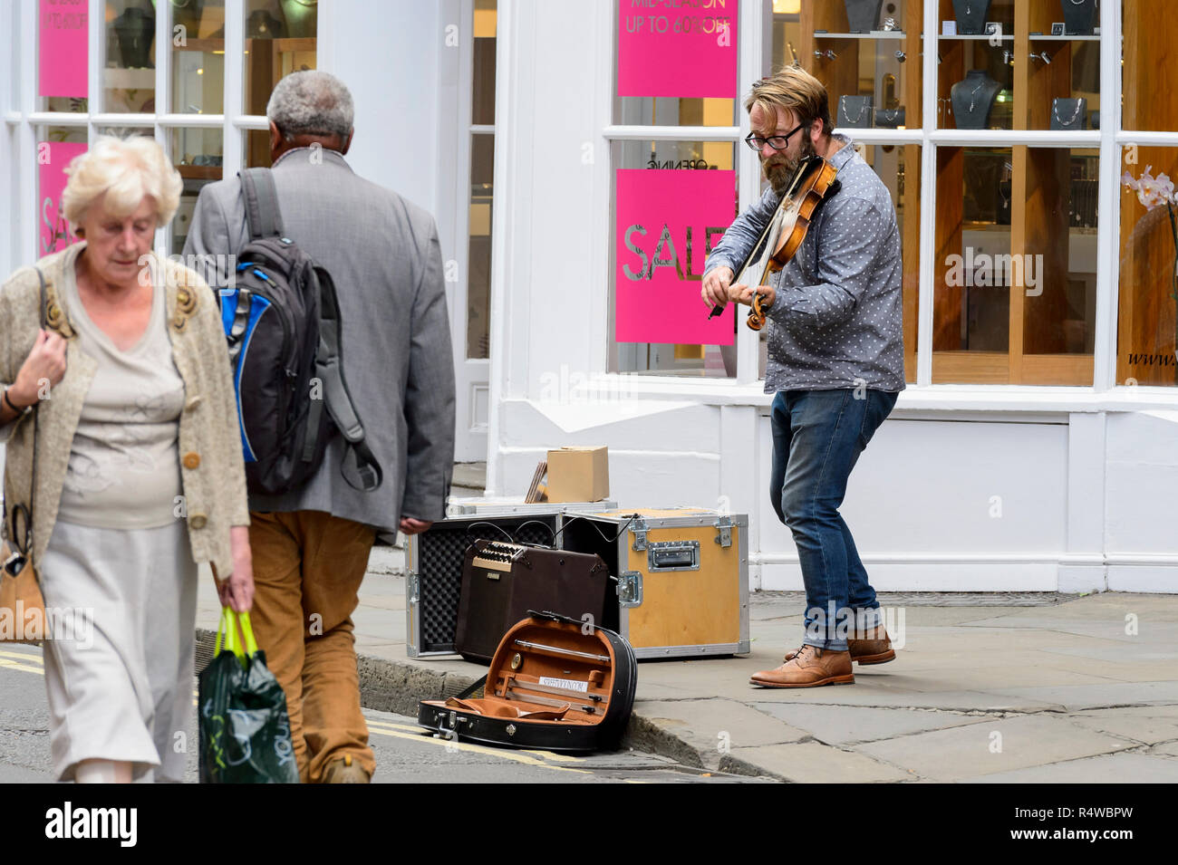 People walk past, ignoring male busker (man busking) standing ...