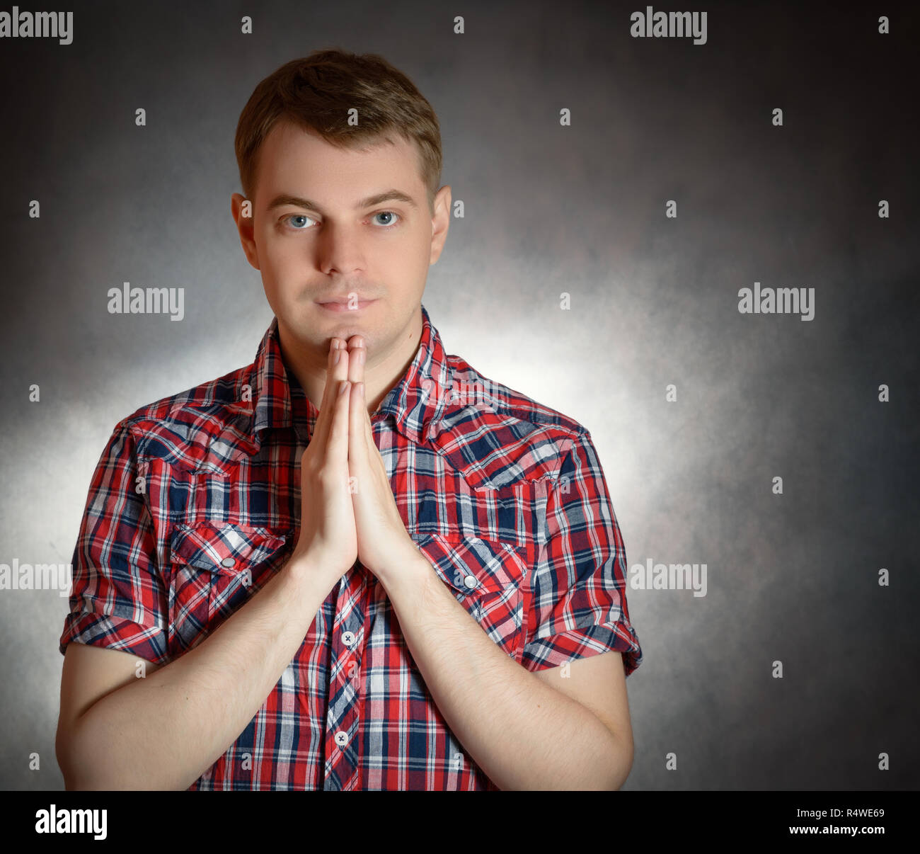 Young man praying on grey background Stock Photo - Alamy