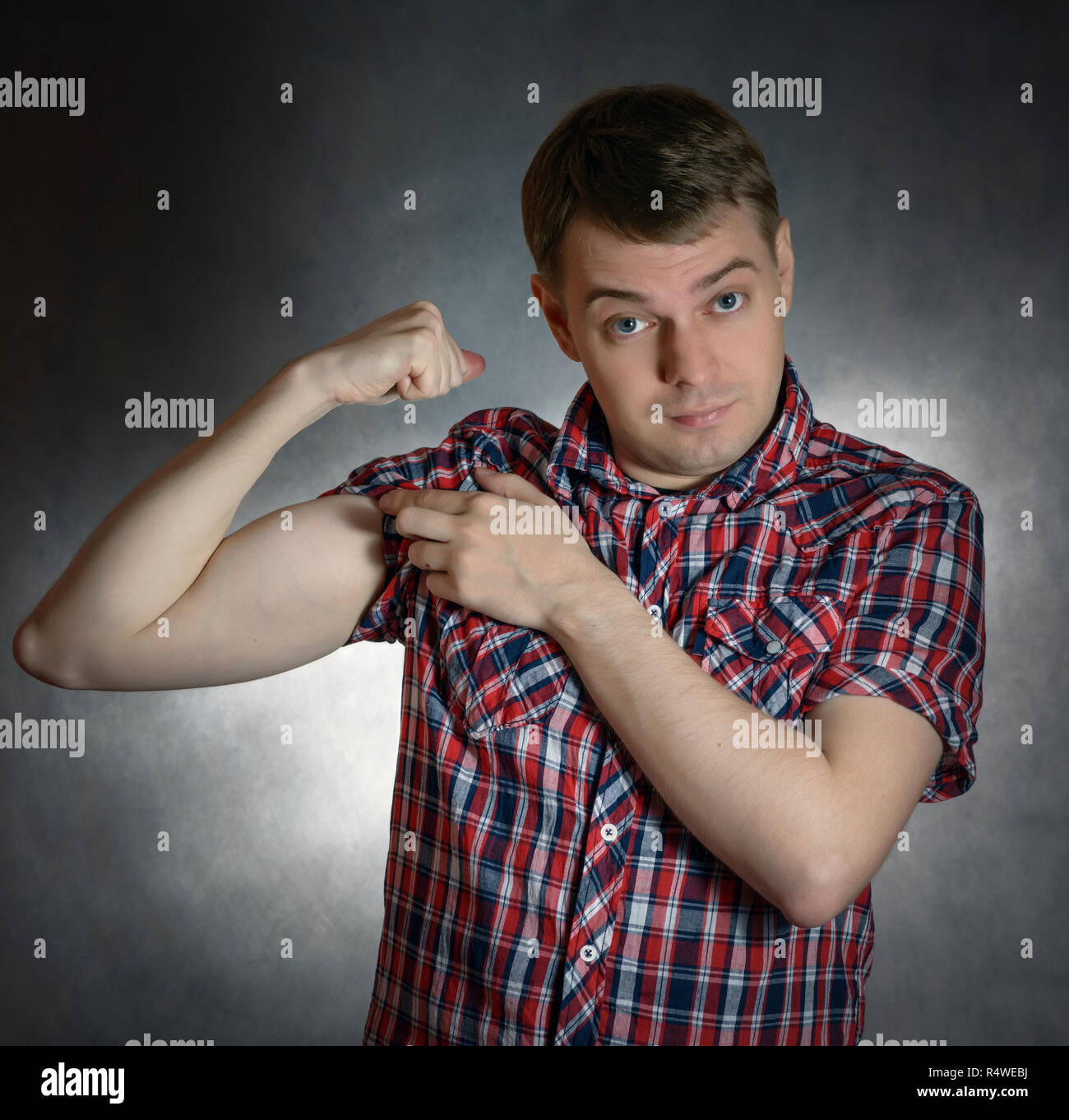 Skinny man showing his muscles on dark grey background Stock Photo - Alamy