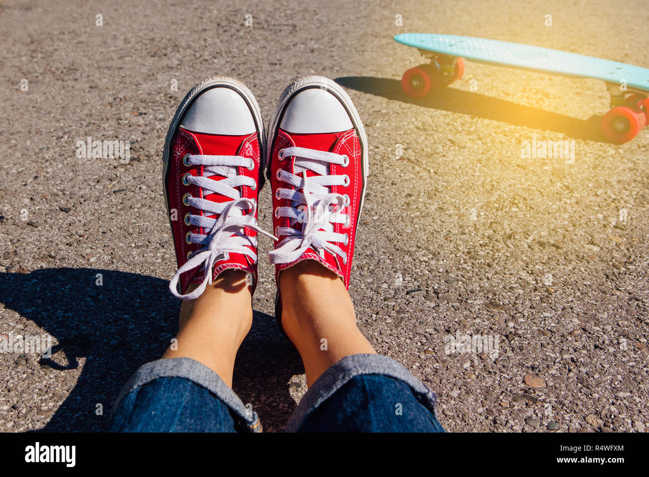 Close up of feet of a girl in red sneakers and blue plastic penny skate ...