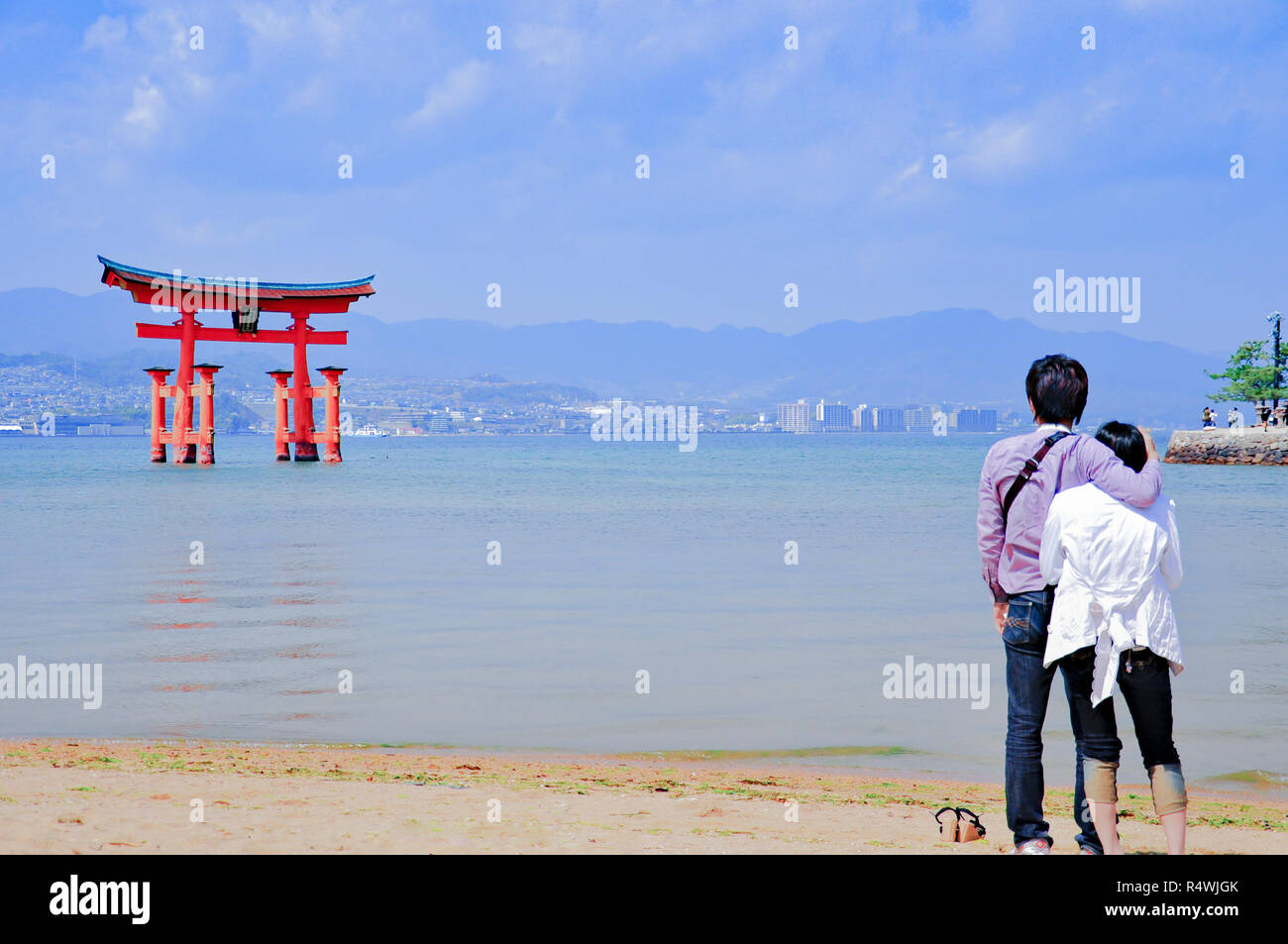 A couple enjoying the view of the floating Torii Gate, Hiroshima, Japan ...