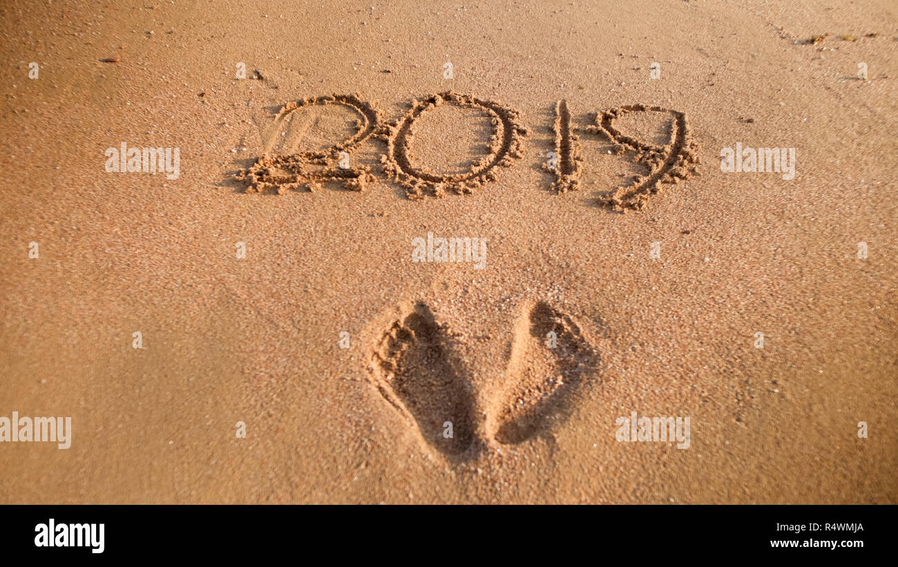 Closeup photo of footprints and 2019 numbers written on wet sand at the ...