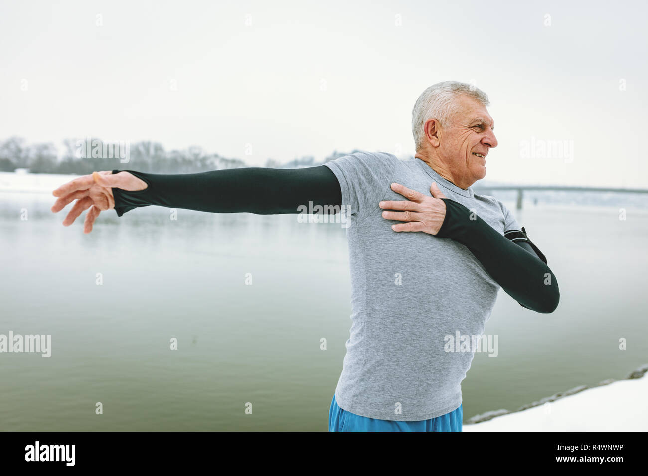 Active senior man stretching and doing exercises by the river during ...
