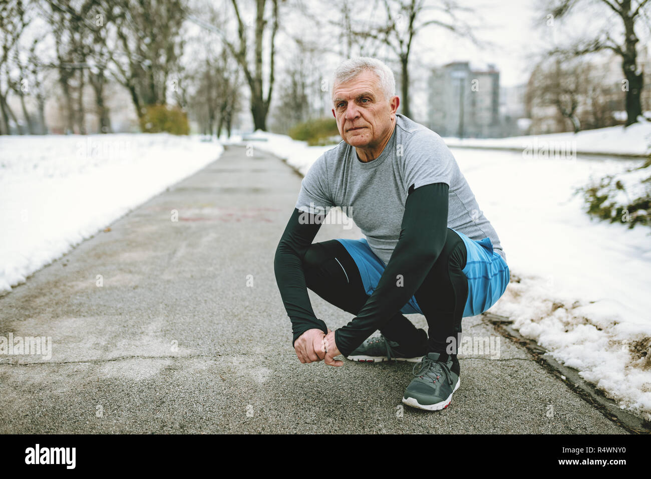 Active senior making pause crouching, during stretching and doing ...