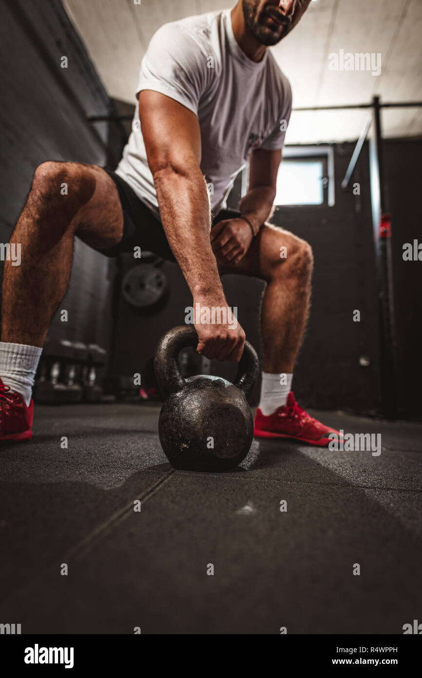 Young muscular man doing hard exercise with kettlebell on cross ...