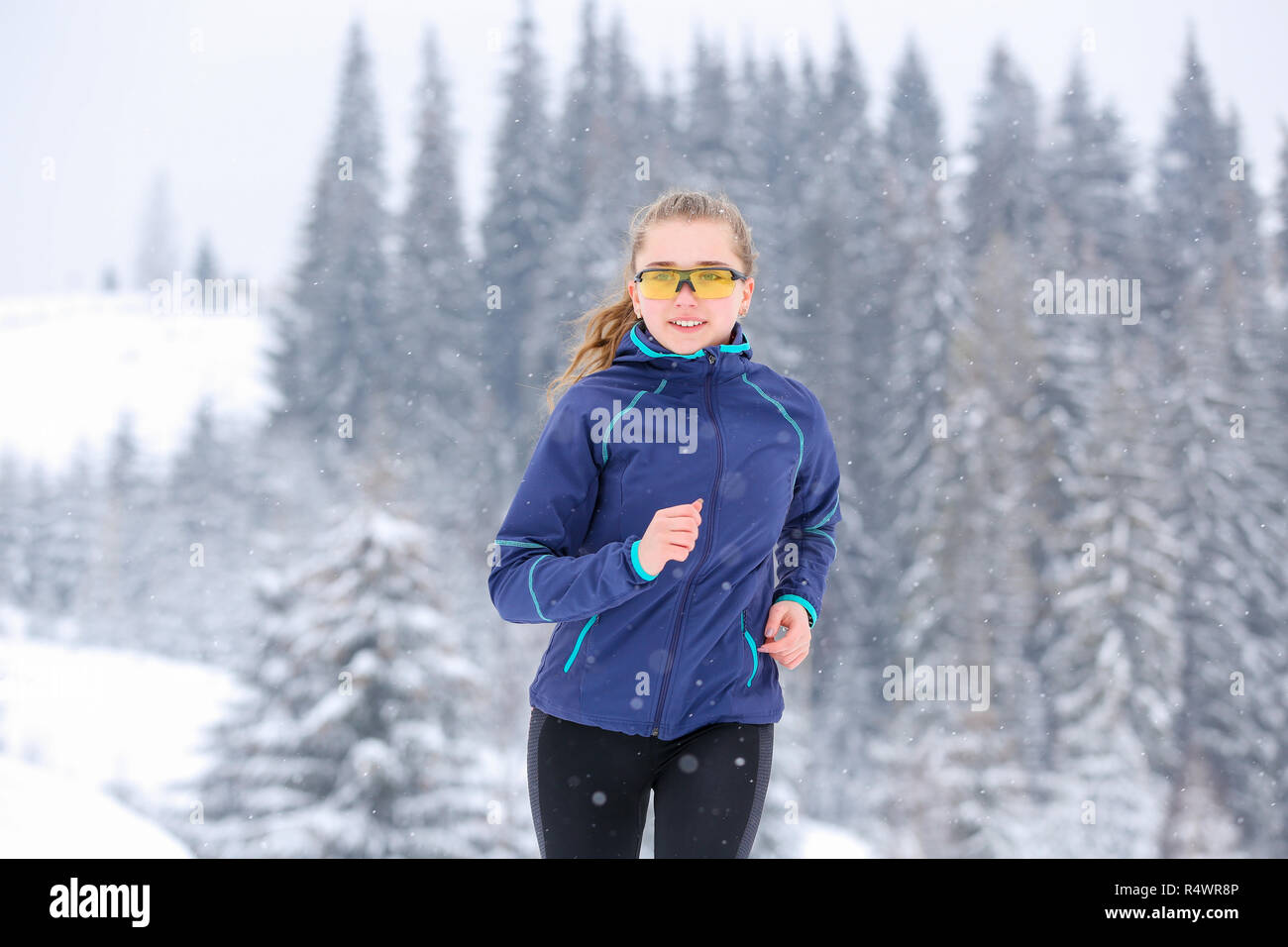 Teenage girl running on winter mountain trail. Smiling girl jogging in ...