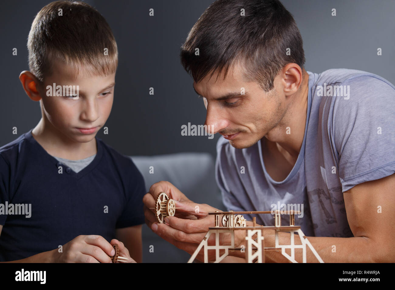 Young boy assembling wooden constructor with his father. Eco building ...