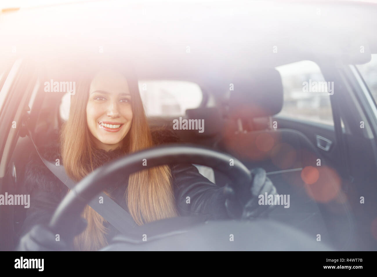Young lady driving a car in winter. Smiling woman steering car view ...