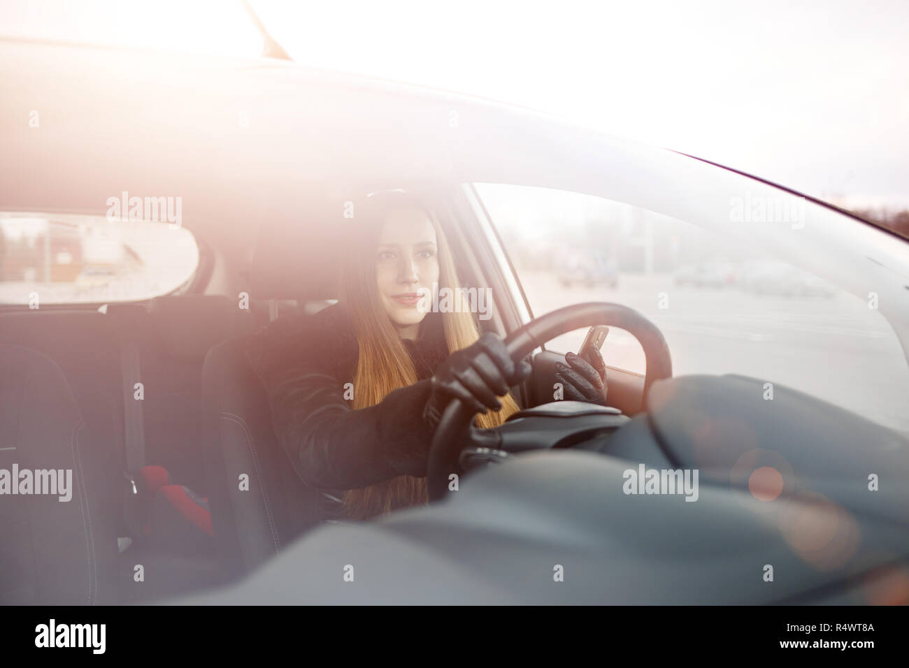 Young lady driving a car in winter. Smiling woman steering car view ...