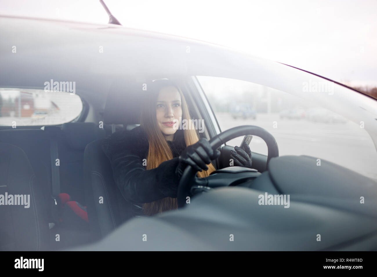 Young lady driving a car in winter. Smiling woman steering car view ...