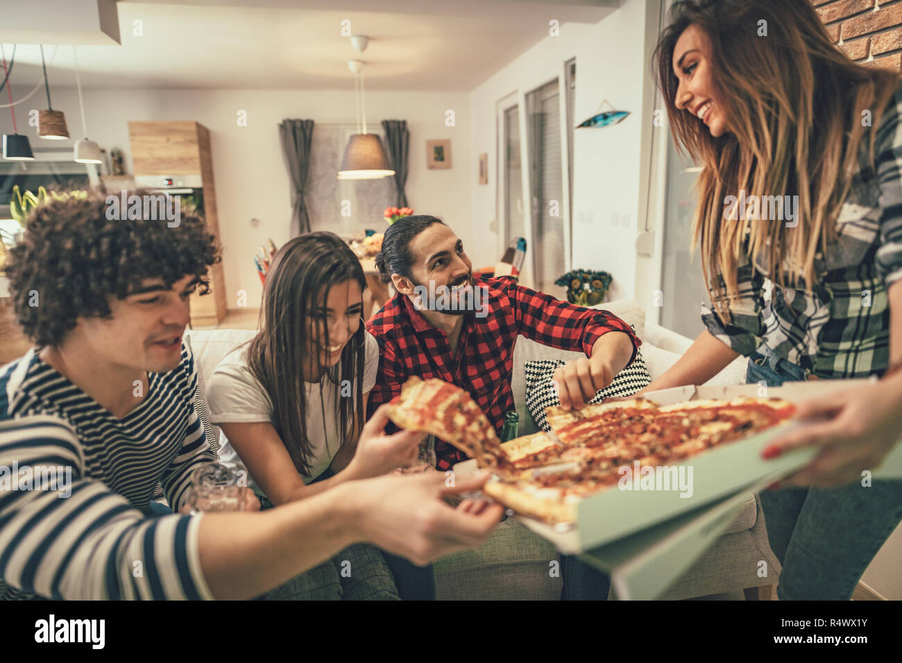 Excited friends is at home sitting on sofa. Their friends bring pizza ...