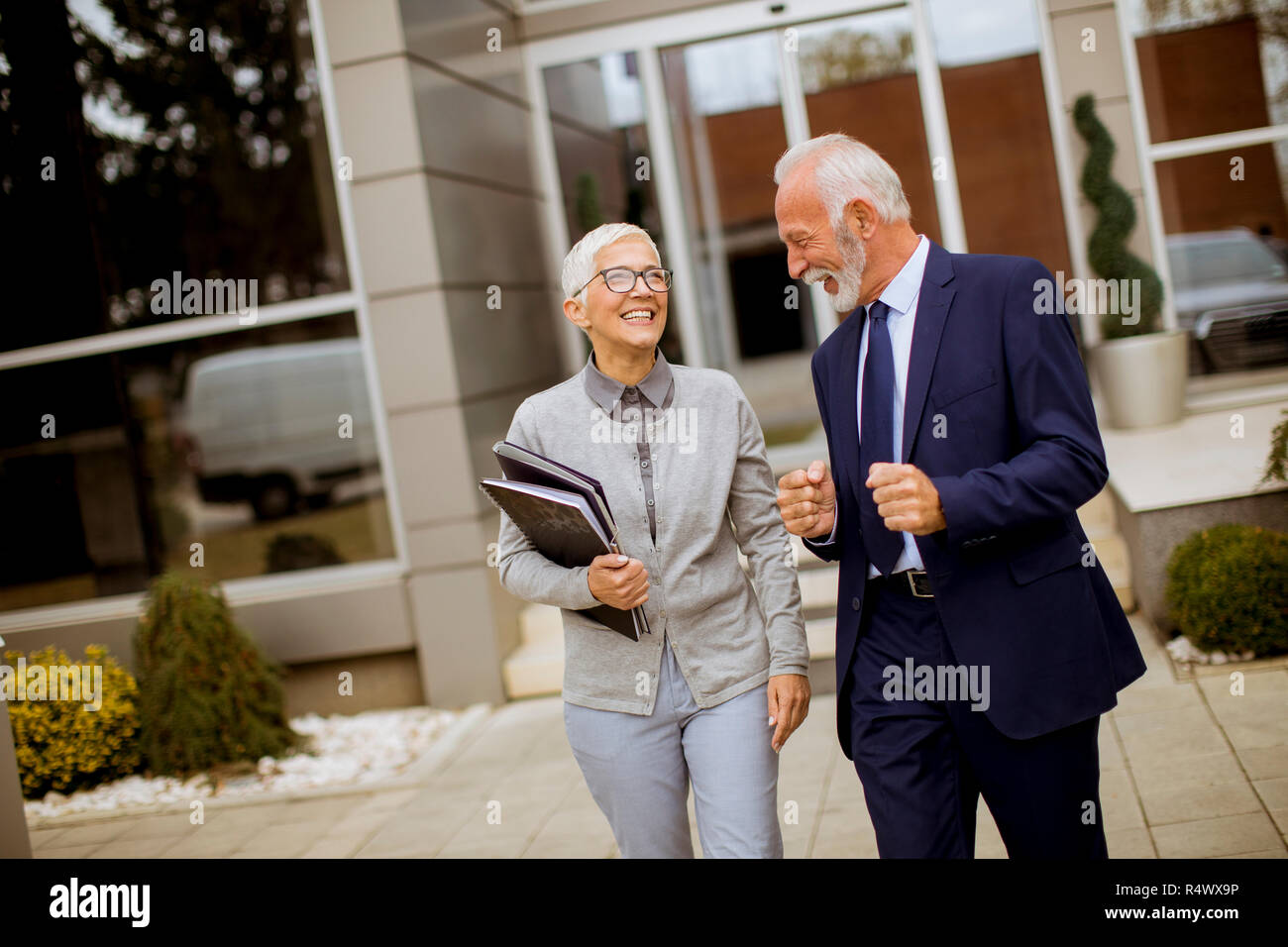 Senior businesspeople standing and talking outdoor office building ...