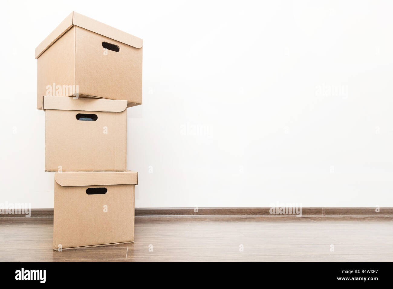 Moving in. Stack of cardboard boxes in the empty room with copy space ...