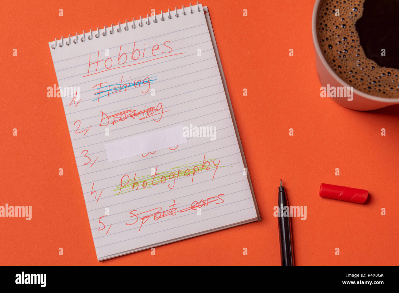 Hobbies list handwritten on a notebook page. Above view with an orange ...