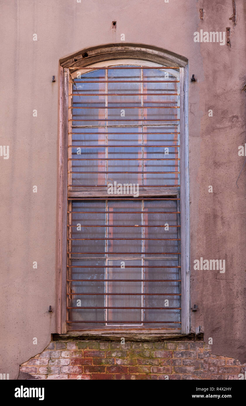 Old window in commercial building with rusted bars covering it, and ...