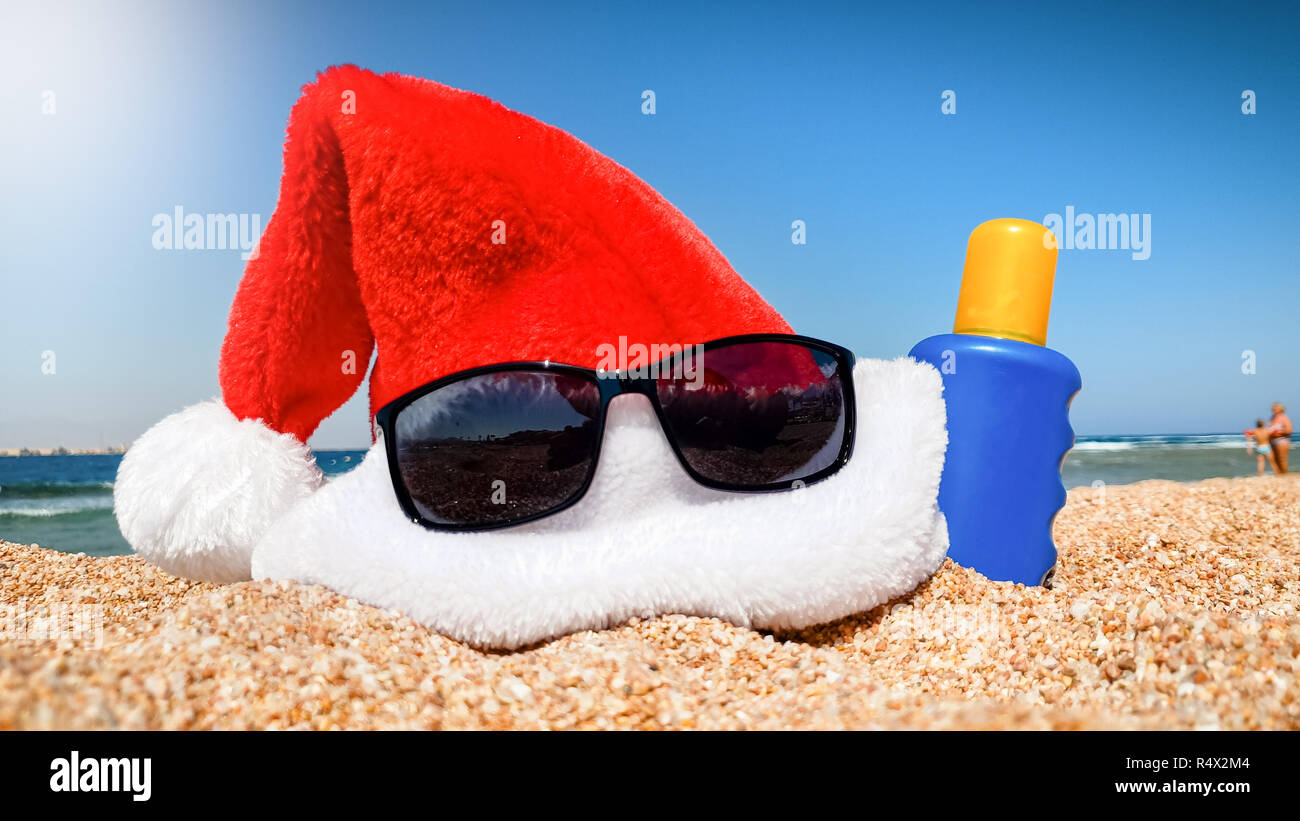 Closeup photo of Santa Claus cap with sunglasses and sunscreen lotion ...
