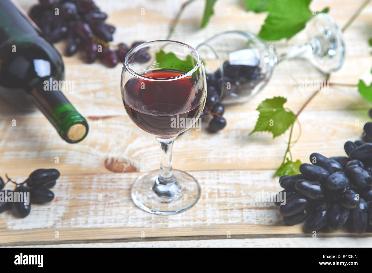 Red wine concept with bottle, glass and grapes on wooden background ...