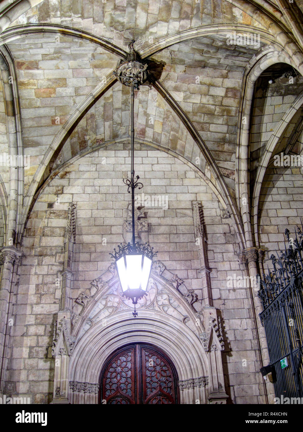 An old wrought iron lamp with an electric light under a pointed vault ...