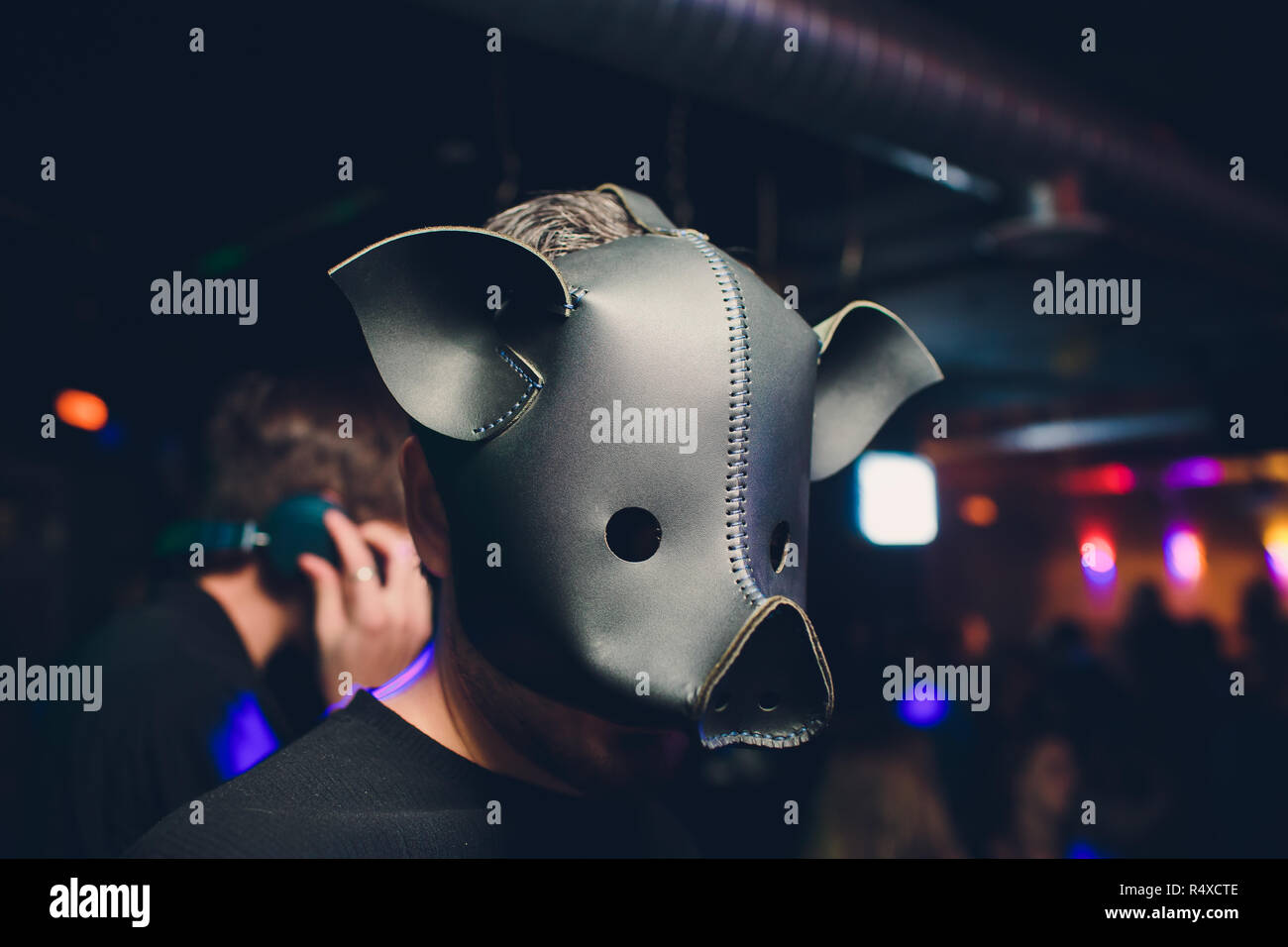A corporate man in a dirty scruffy suit wearing a black pigs mask in a ...