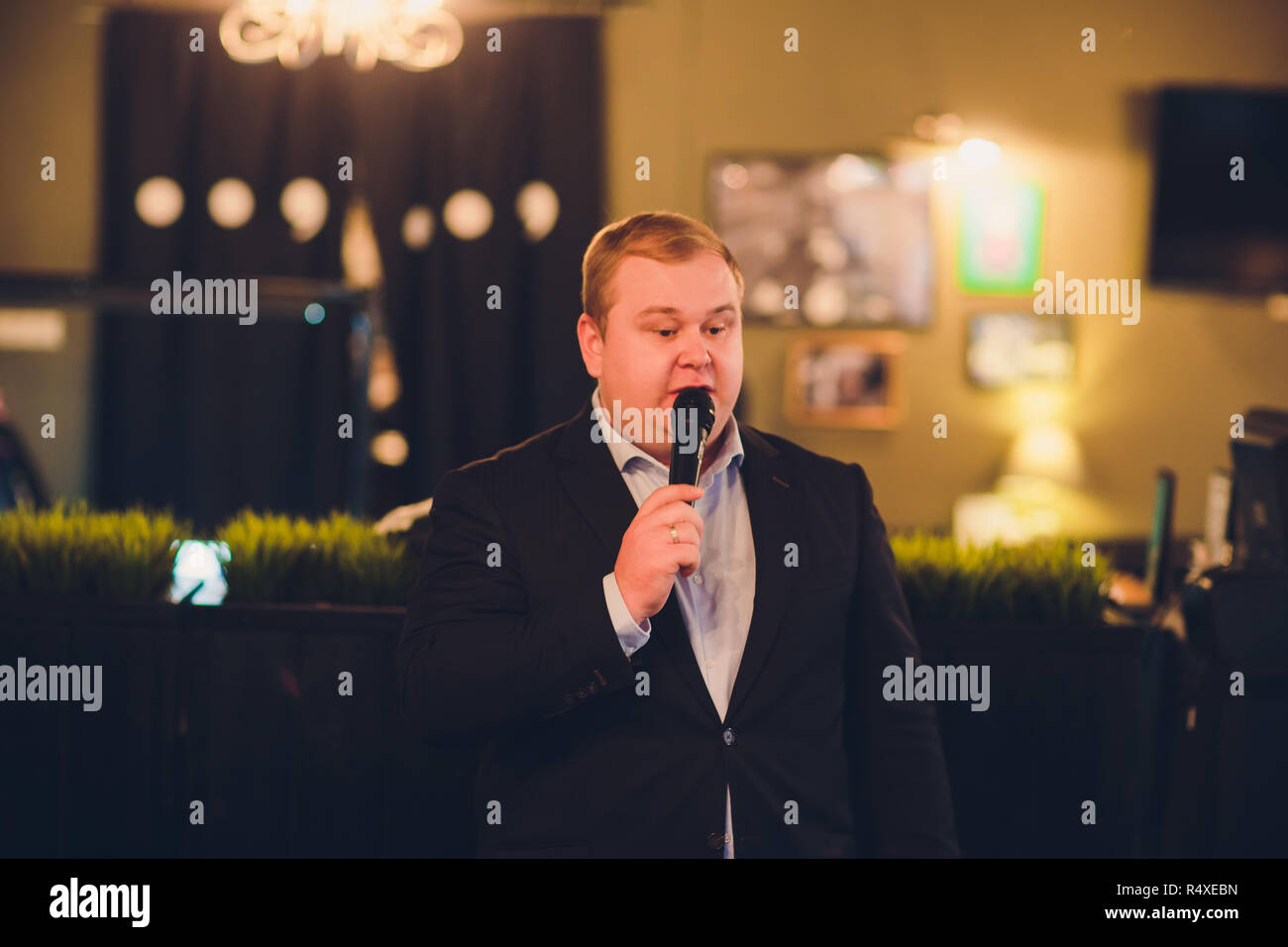 Young man with microphone on gray background, leading with microphone ...