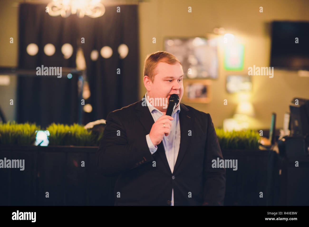 Young man with microphone on gray background, leading with microphone ...