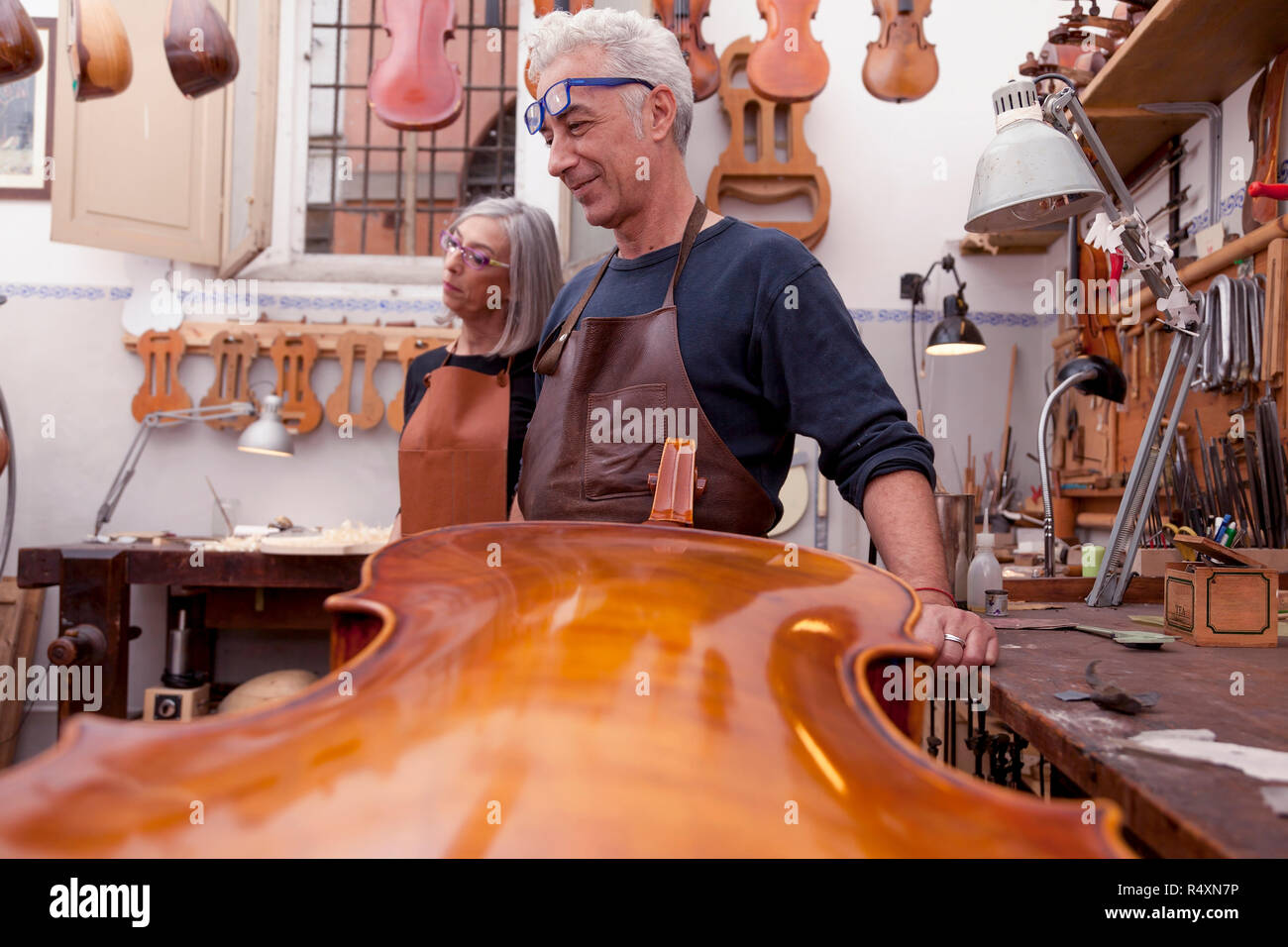 portrait of mature violin maker while testing the violins in his ...